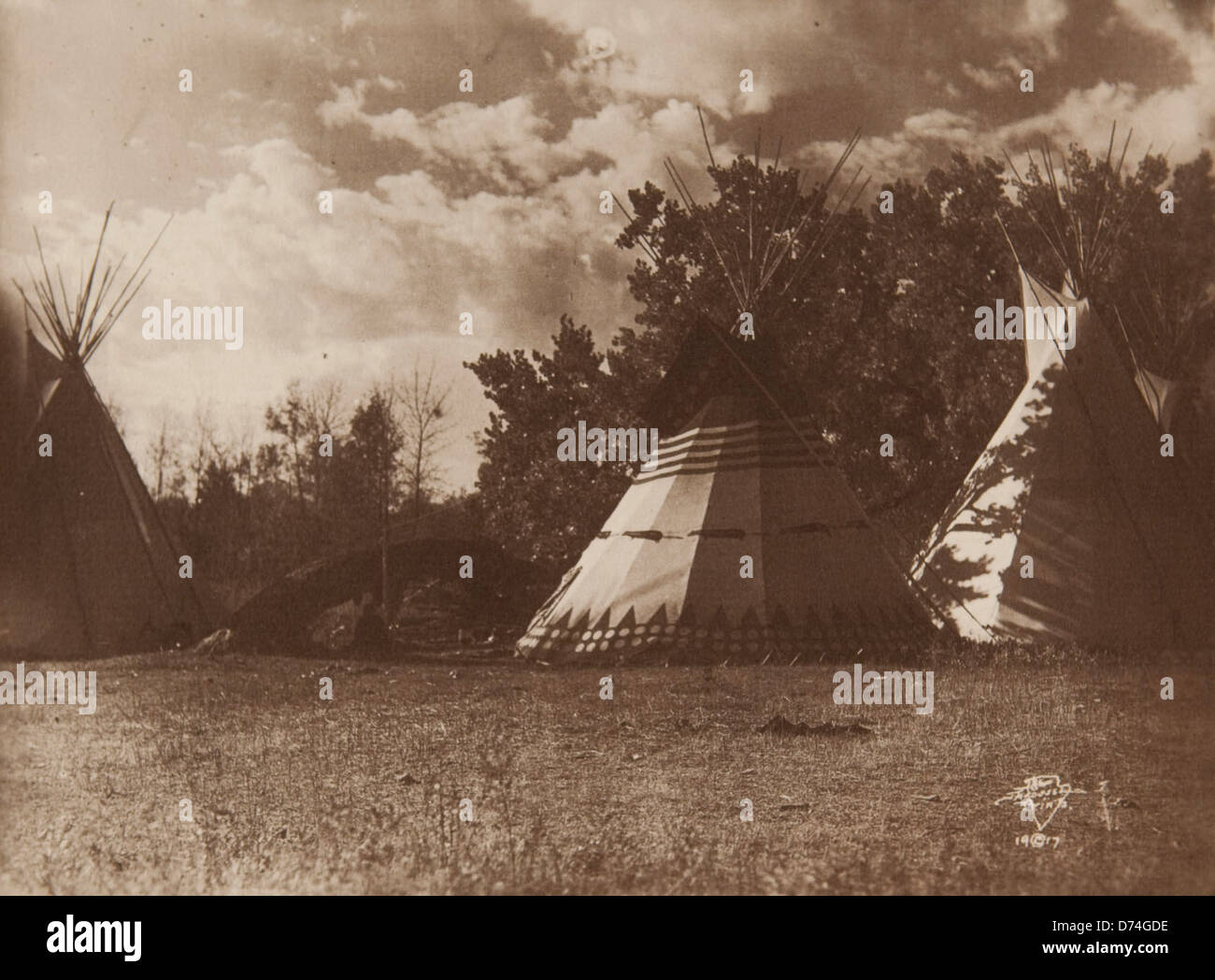 This untitled photograph depicts tepees set against a cloudy sky ...