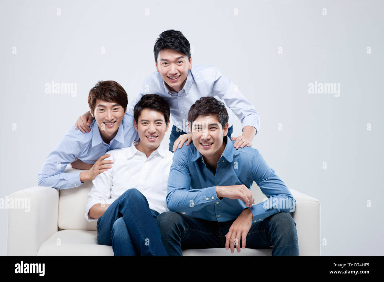 four men sitting on a couch posing at camera Stock Photo - Alamy