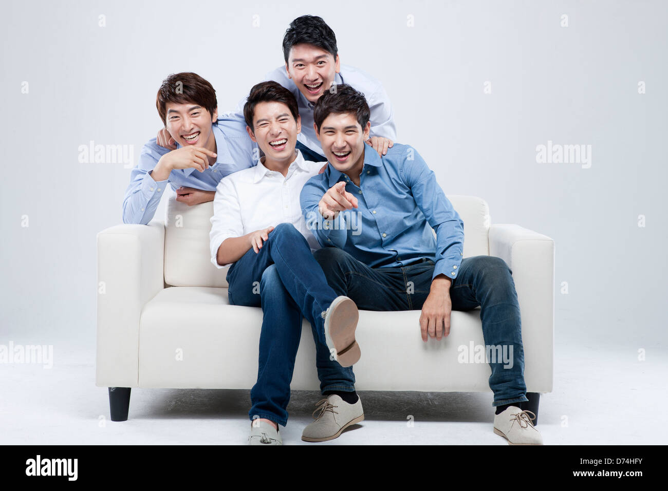 four men sitting on a couch posing at camera Stock Photo - Alamy