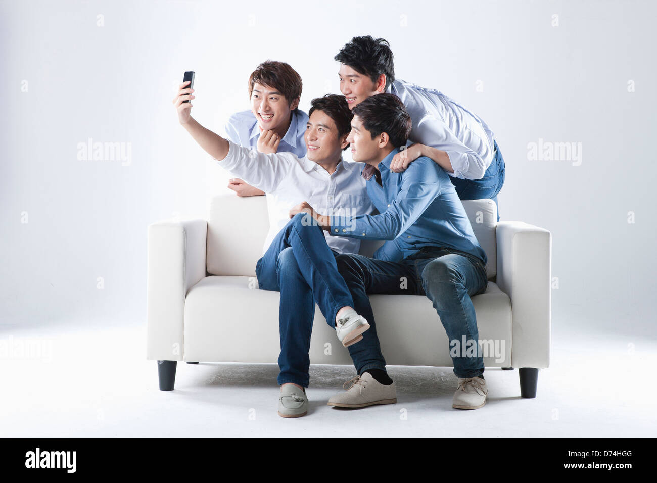 four men sitting on a couch taking a picture Stock Photo - Alamy