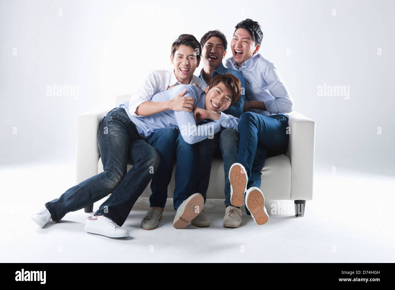 four men sitting on a couch having fun Stock Photo - Alamy