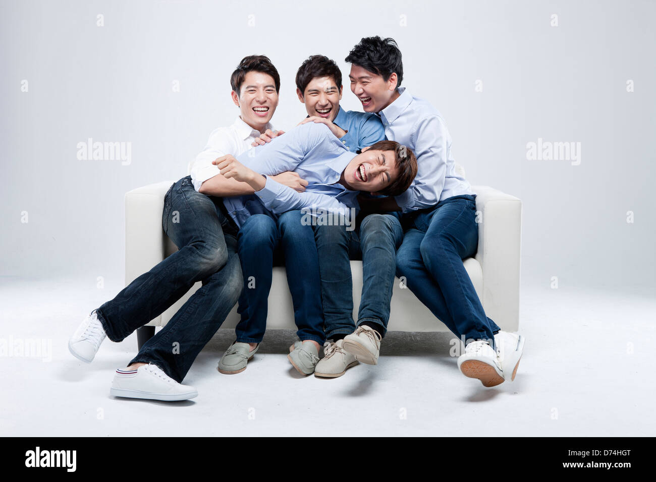 four men sitting on a couch having fun Stock Photo - Alamy