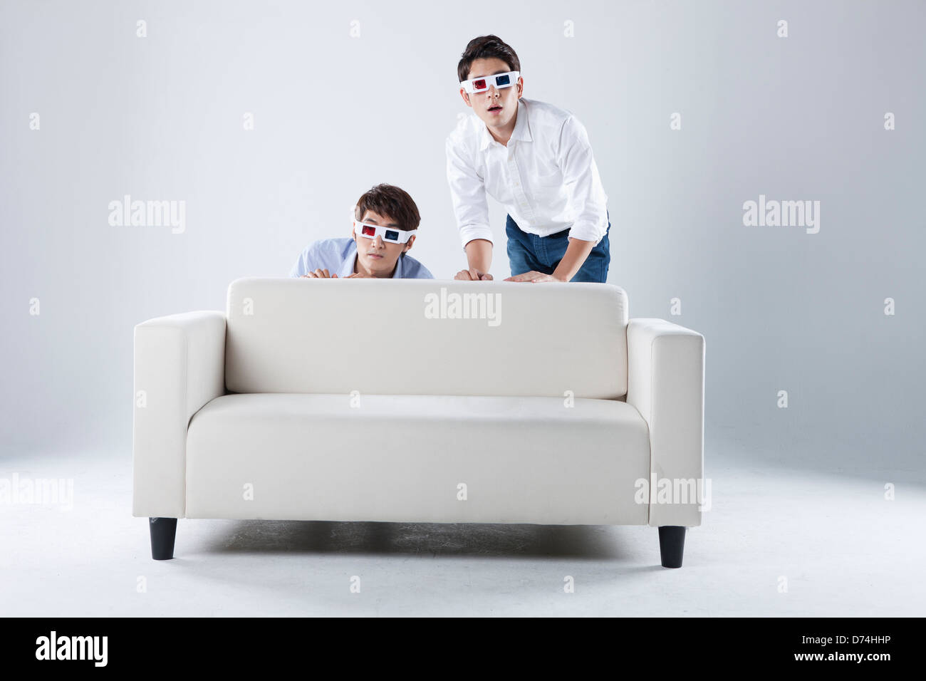 two men hiding behind a couch watching TV with 3D glasses Stock Photo ...