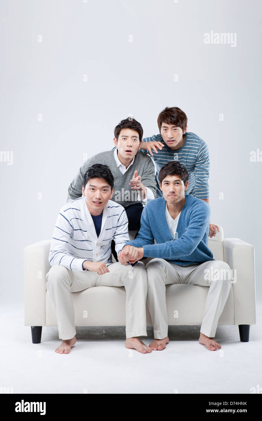 four men on and around a couch watching a TV Stock Photo - Alamy