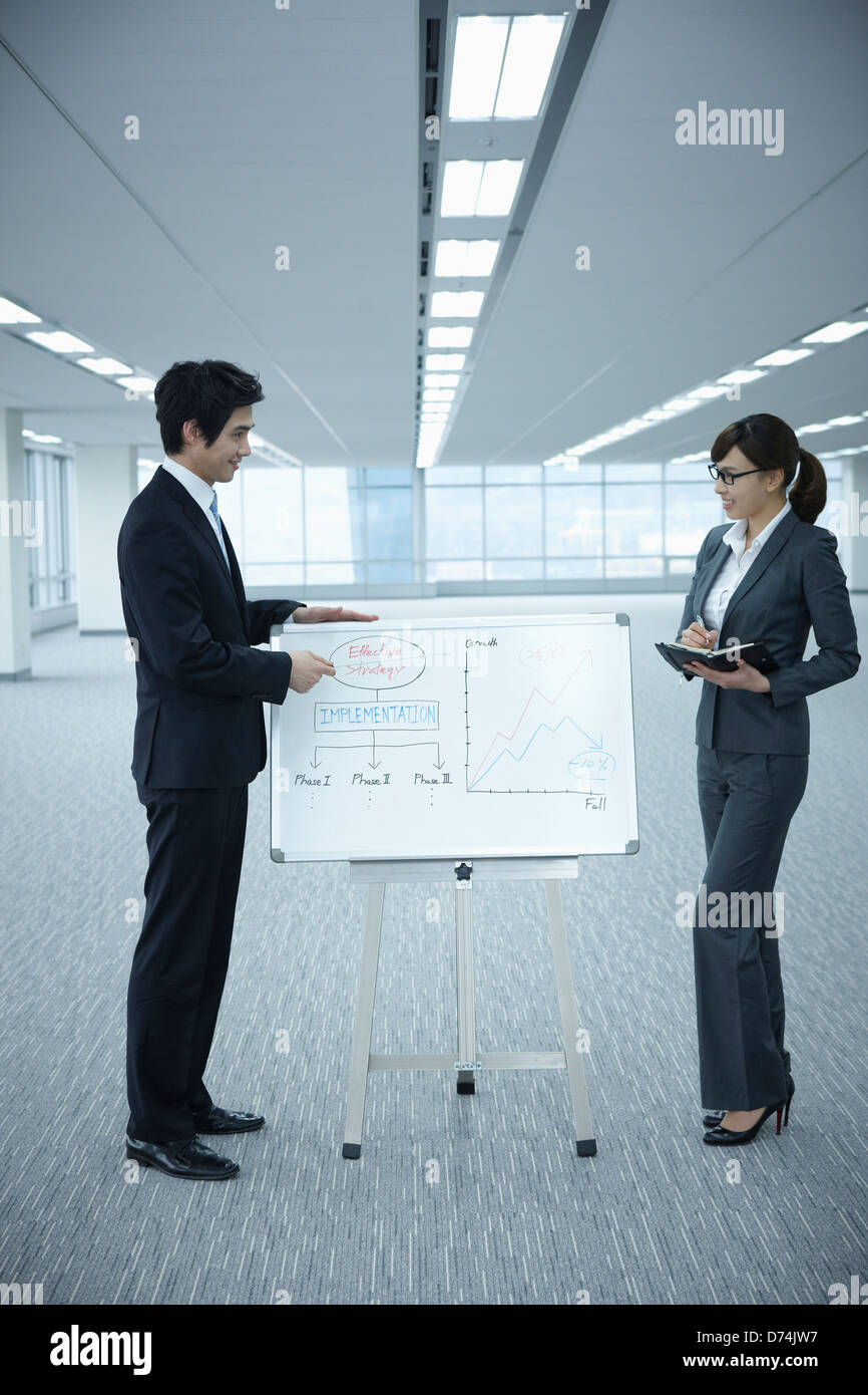 businessman and businesswoman explaining using a whiteboard in an empty ...