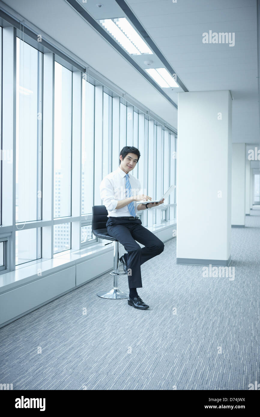 a businessman sitting on a chair with a laptop in an empty office Stock ...