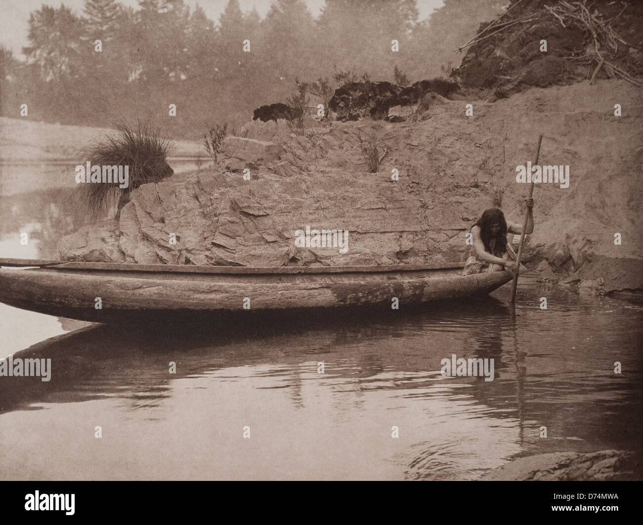 This image features a member of the Hupa tribe fishing from a canoe ...