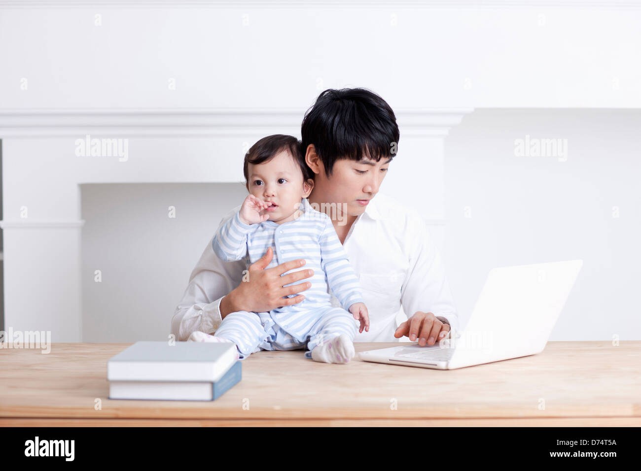 father using laptop with a baby on table Stock Photo - Alamy