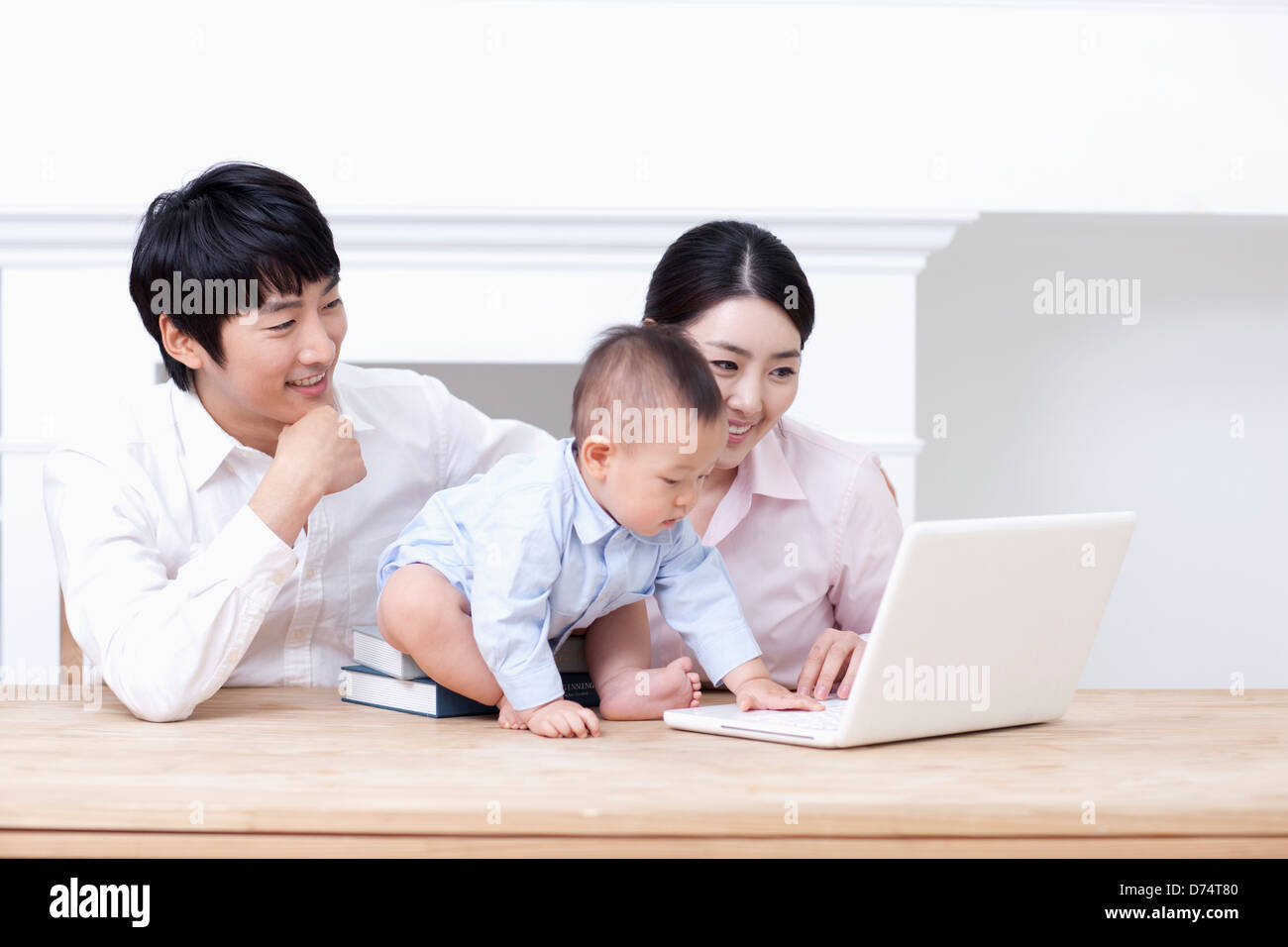 parents using laptop with a baby on table Stock Photo - Alamy