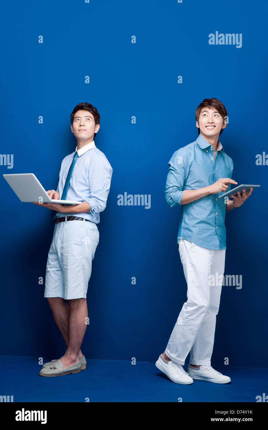 a man with laptop and a man with tablet PC in blue background Stock ...