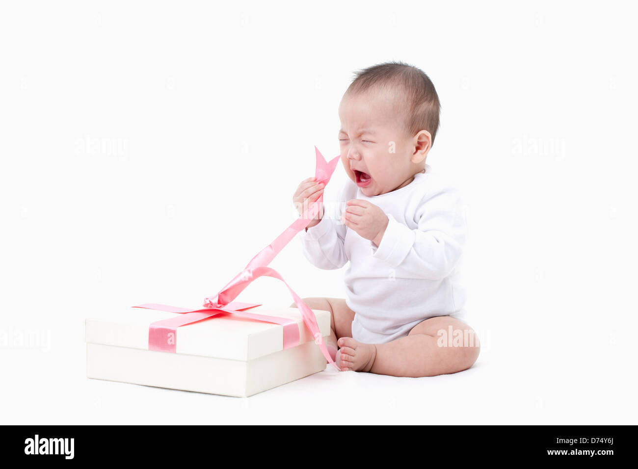 a baby pulling ribbon off from a gift with mouth Stock Photo - Alamy