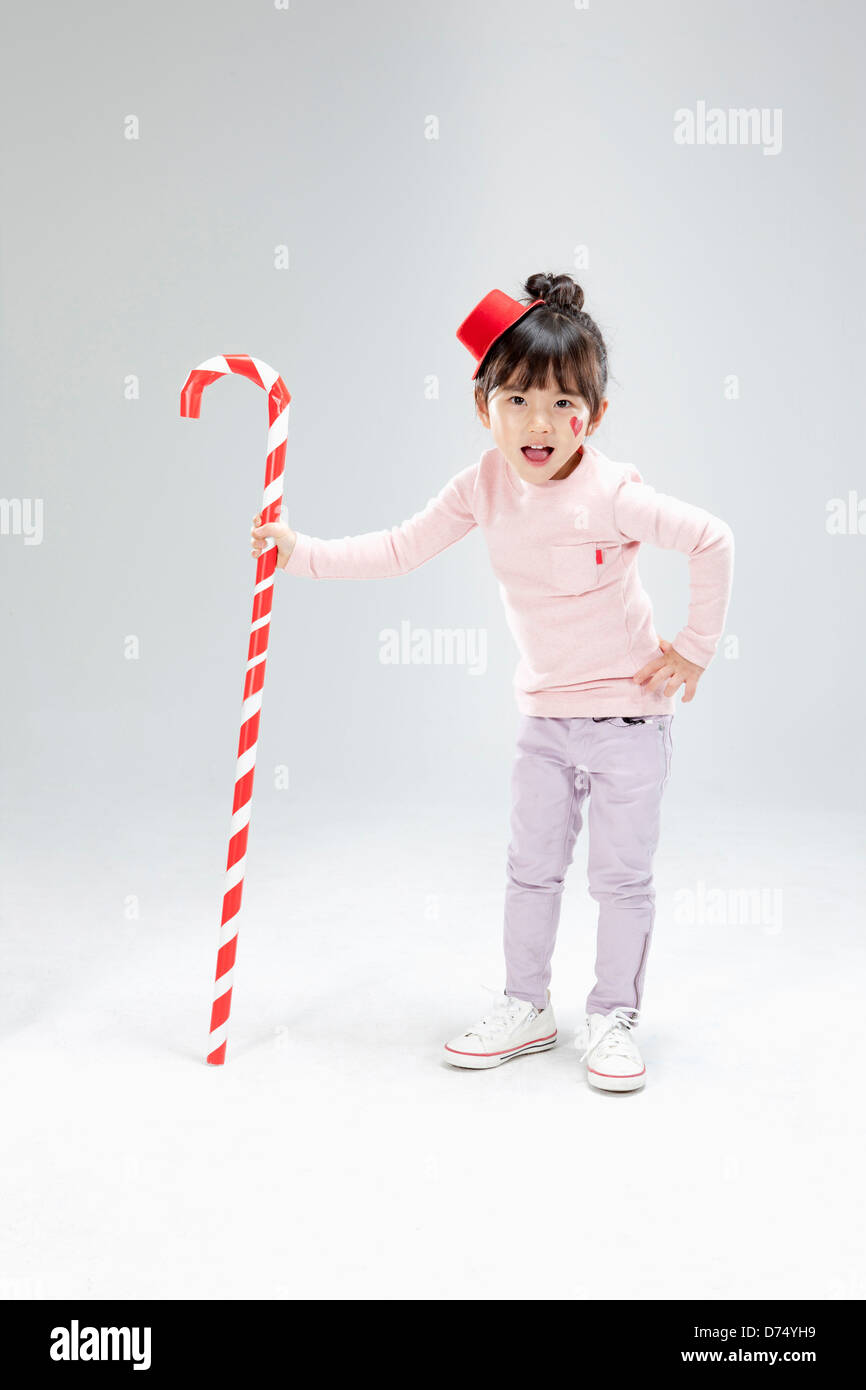 a girl with small red hat posing with a big candy cane Stock Photo - Alamy