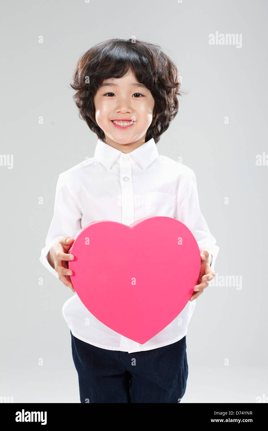a boy in white shirts holding a heart shaped box Stock Photo - Alamy