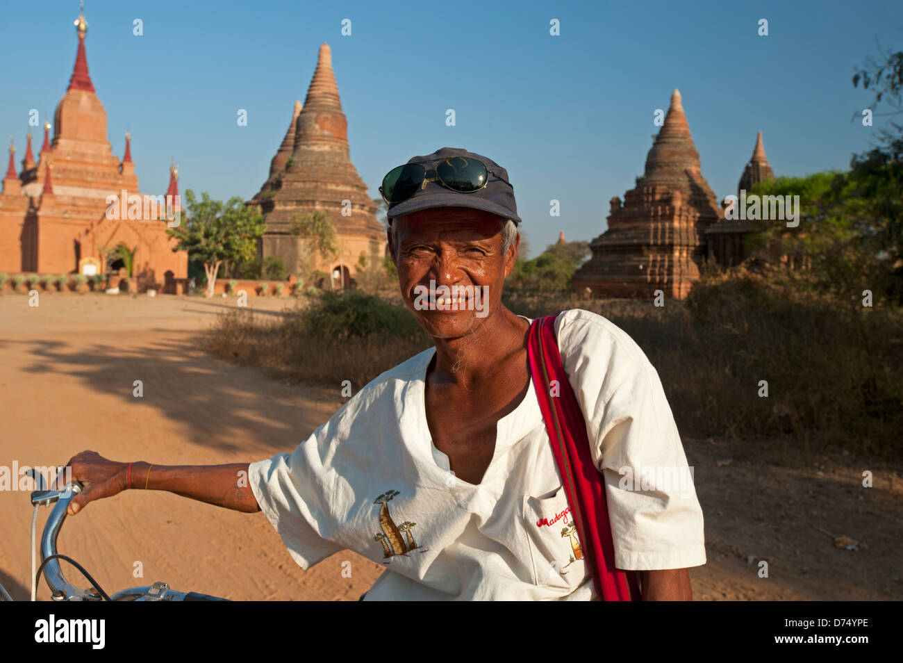 Burmese man and his bicycle standing in front of stone temples at ...