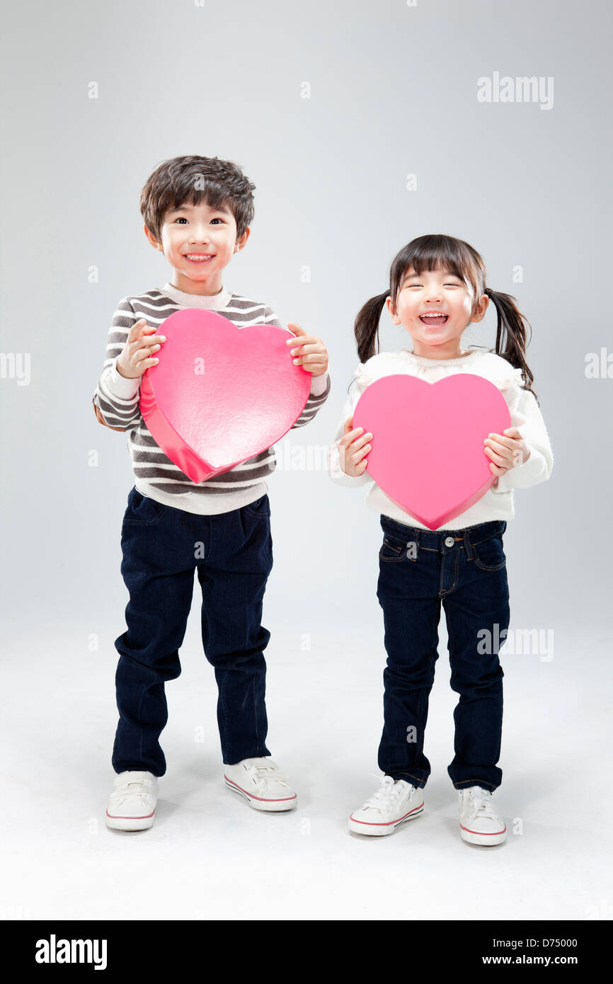 girls and boy holding heart shaped boxes Stock Photo - Alamy