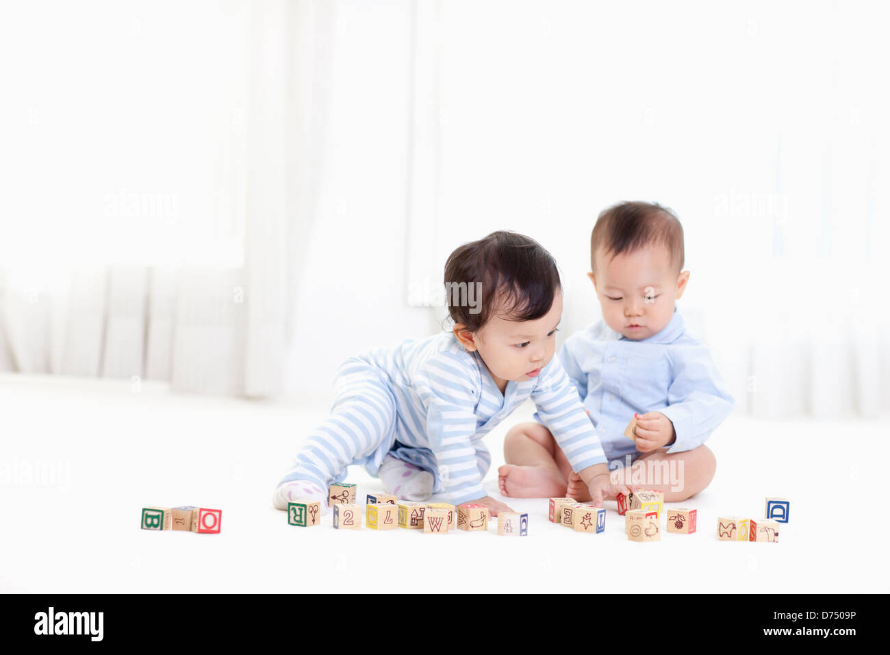 two babies playing with blocks on the floor Stock Photo - Alamy