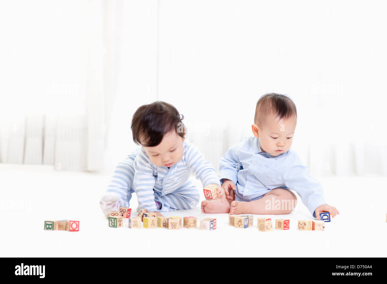 two babies playing with blocks on the floor Stock Photo - Alamy
