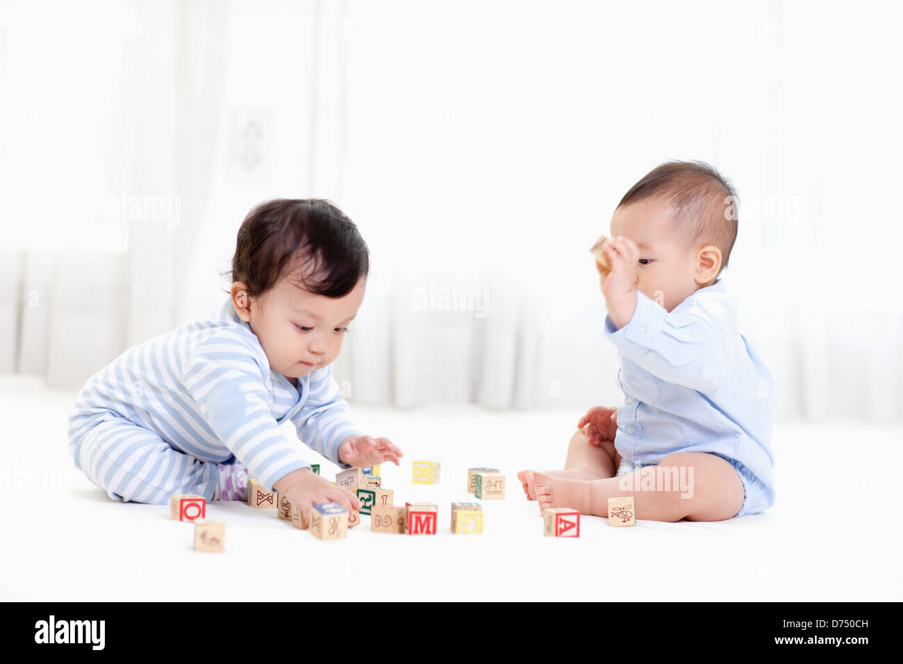 two babies playing with blocks on the floor Stock Photo - Alamy