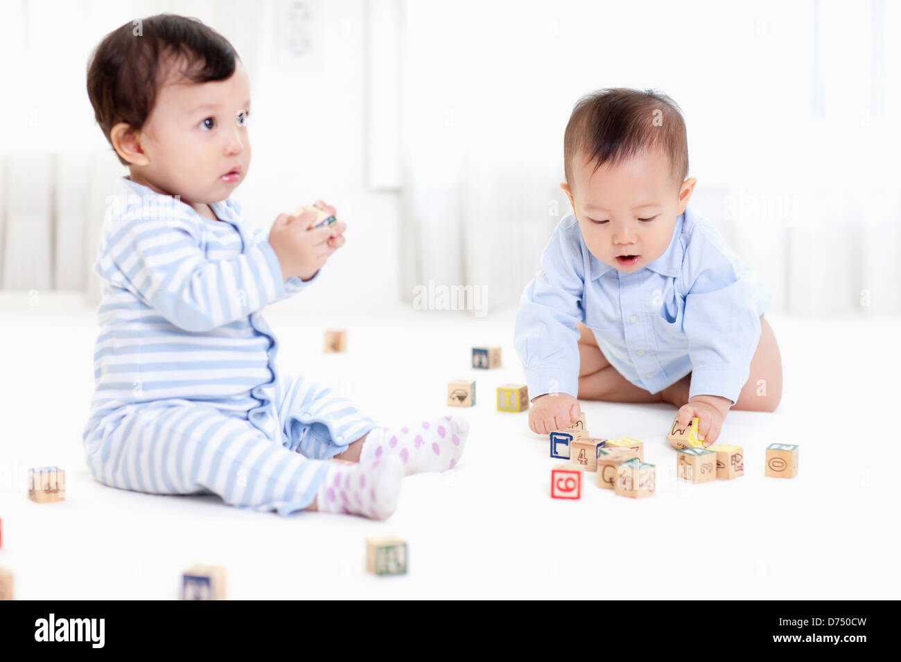 two babies playing with blocks on the floor Stock Photo - Alamy
