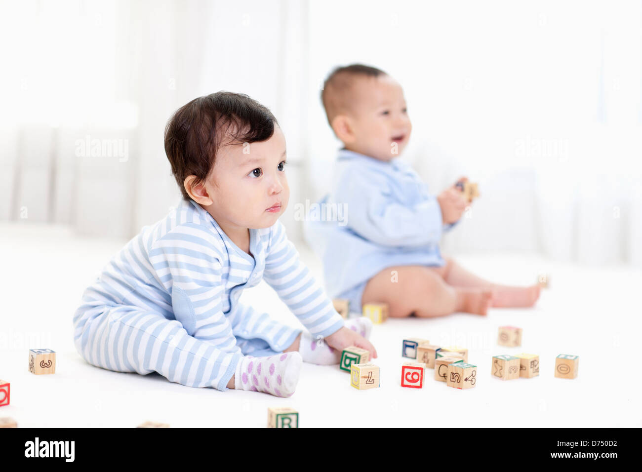 two babies playing with blocks on the floor Stock Photo - Alamy