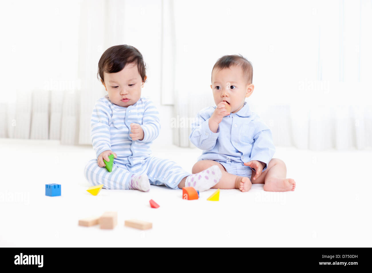two babies playing with blocks and shapes on the floor Stock Photo - Alamy