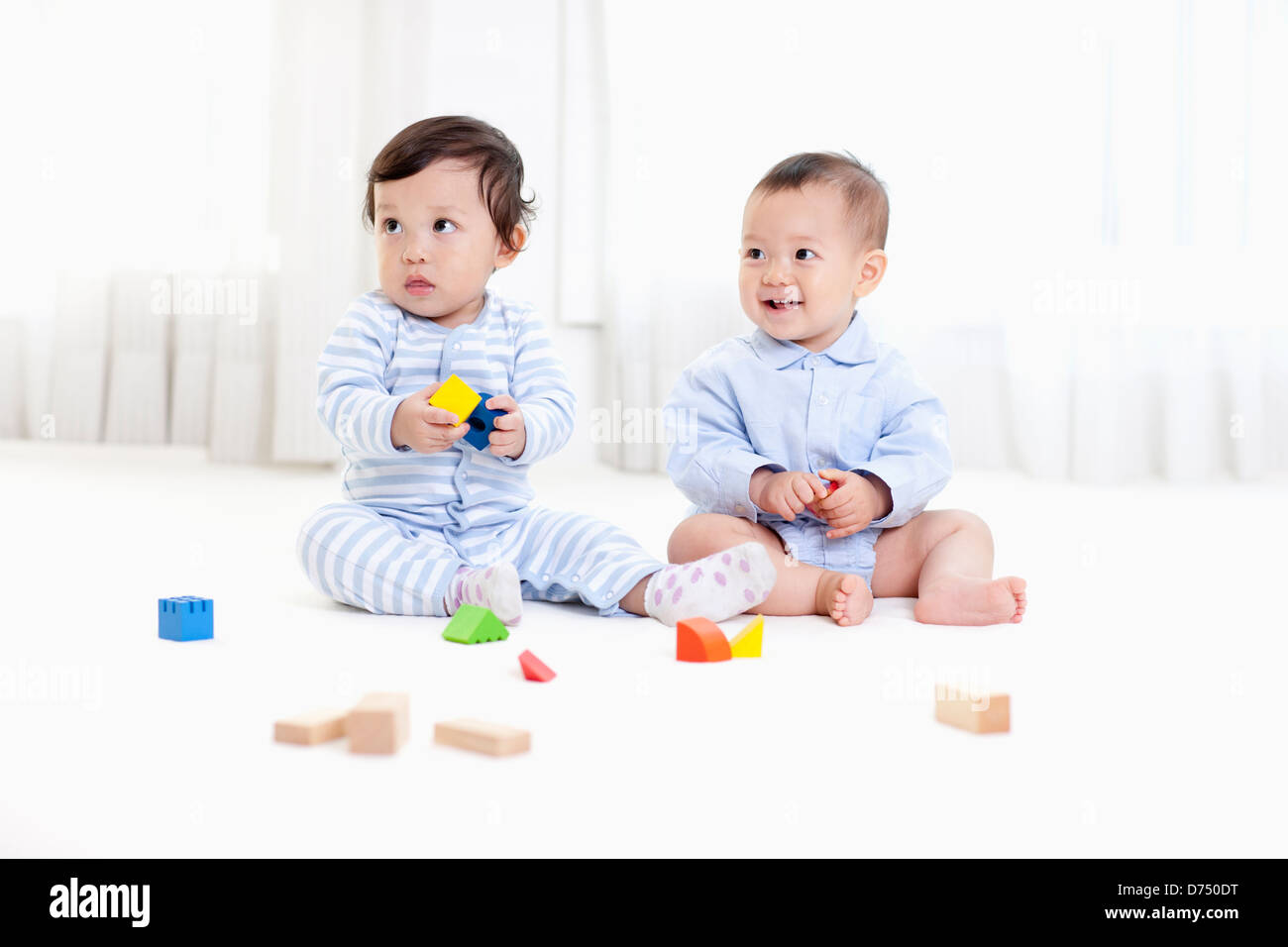two babies playing with blocks and shapes on the floor Stock Photo - Alamy
