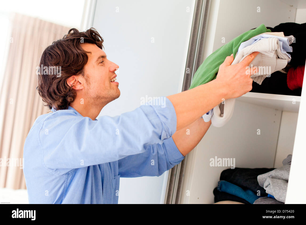 Man organizing clothes in cupboard Stock Photo - Alamy