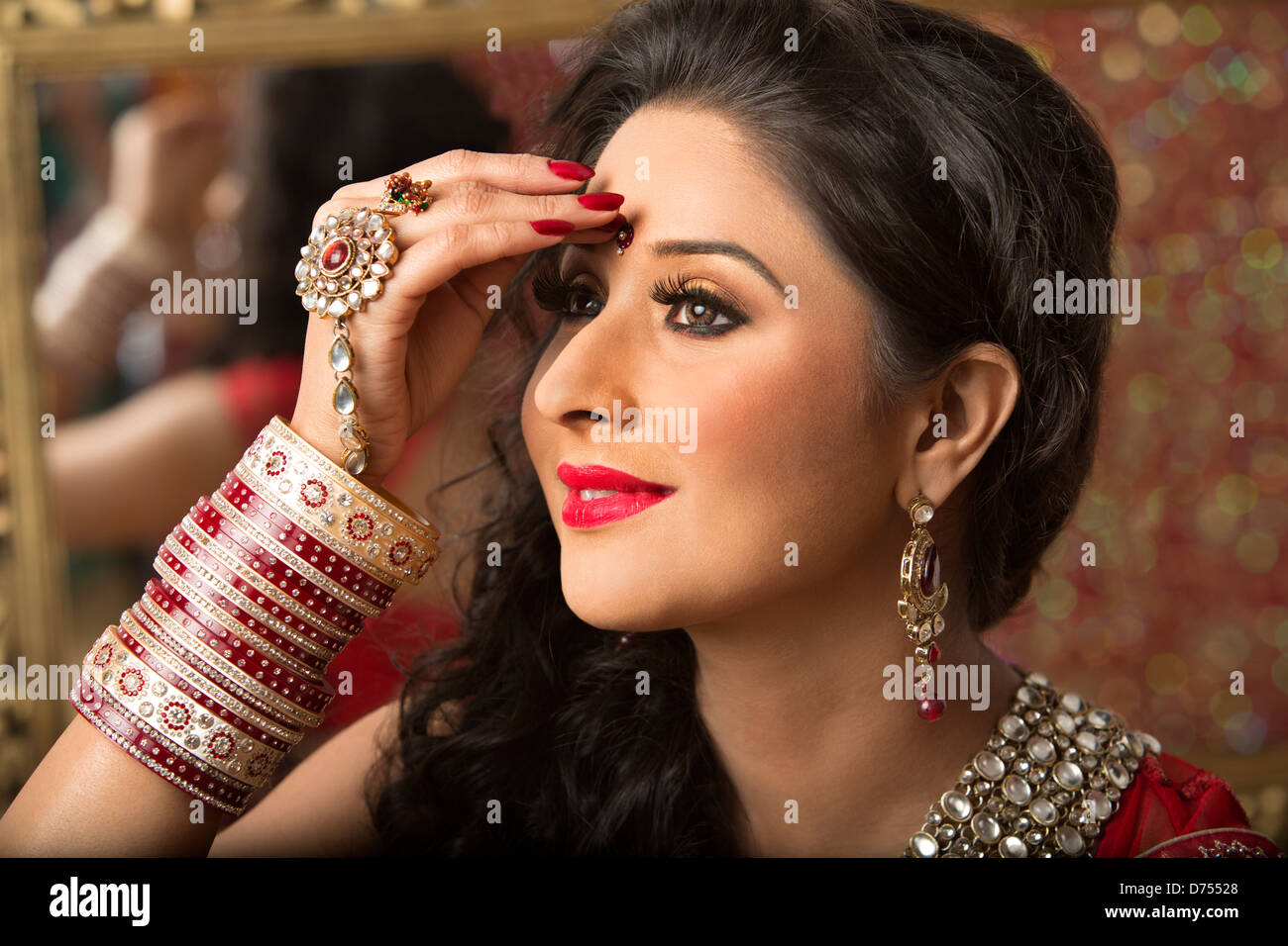 Bridal woman putting on bindi on her forehead Stock Photo - Alamy