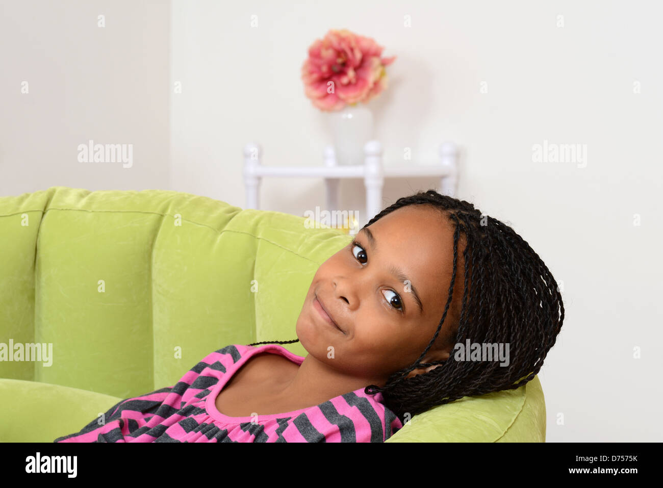 Young black child relaxing in green chair Stock Photo - Alamy