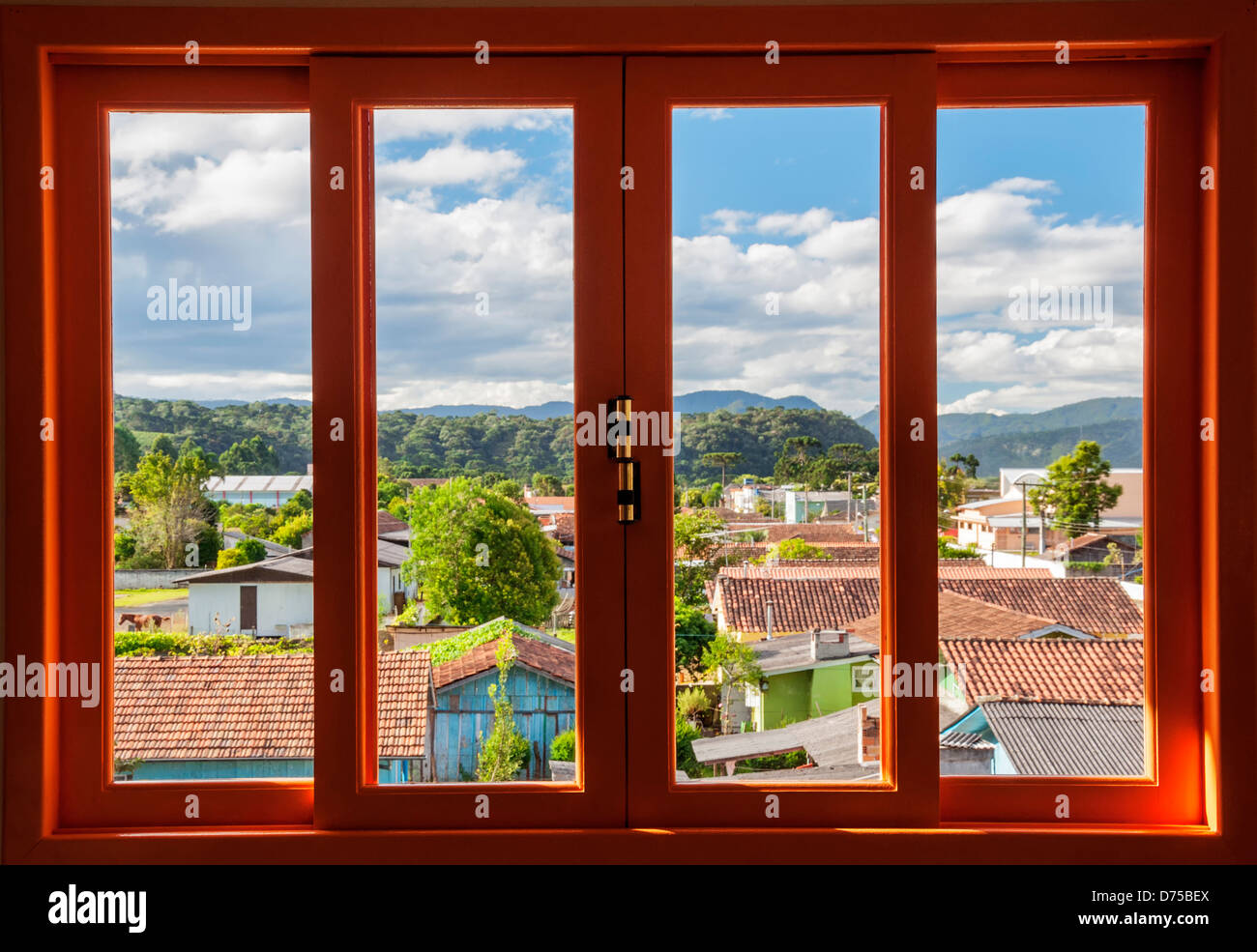 View of a small town through a window with red frame in Urubici, Brazil ...