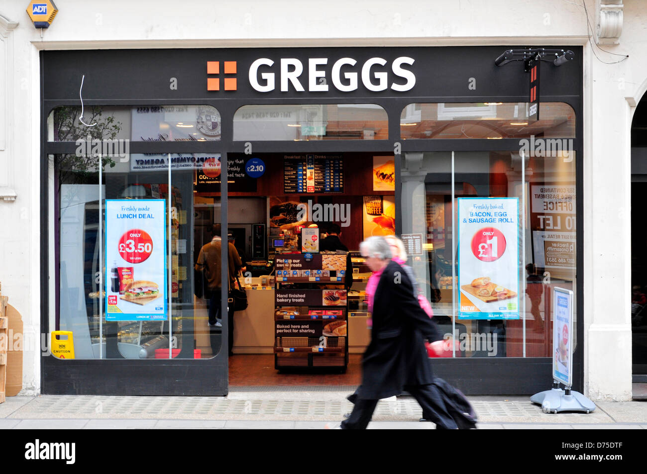 Two women walk past Greggs, the bakery chain. London, UK Stock Photo ... Two women walk past Greggs, the bakery chain. London, UK Stock Photo ...
