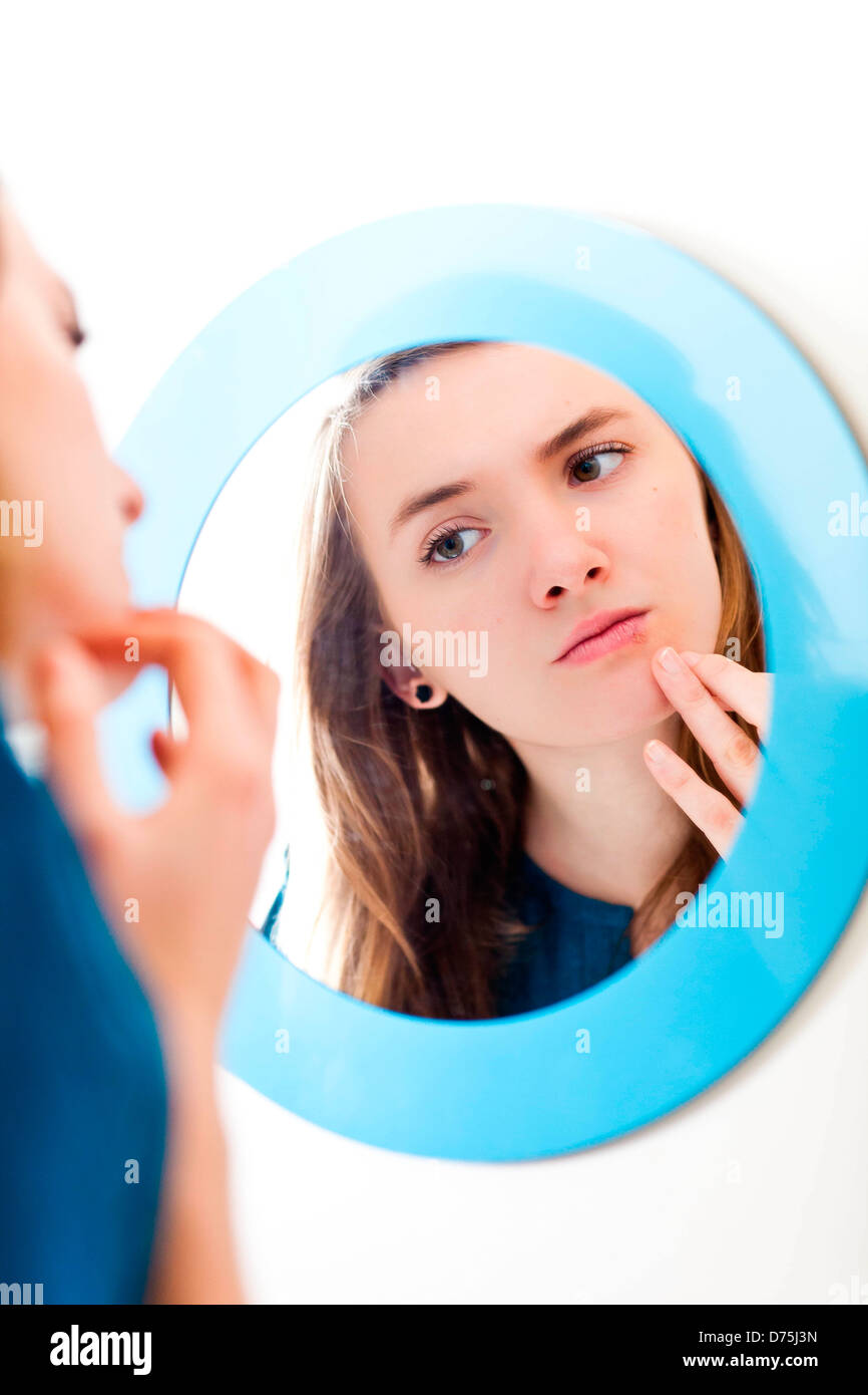 Young woman checking her face in the mirror Stock Photo - Alamy