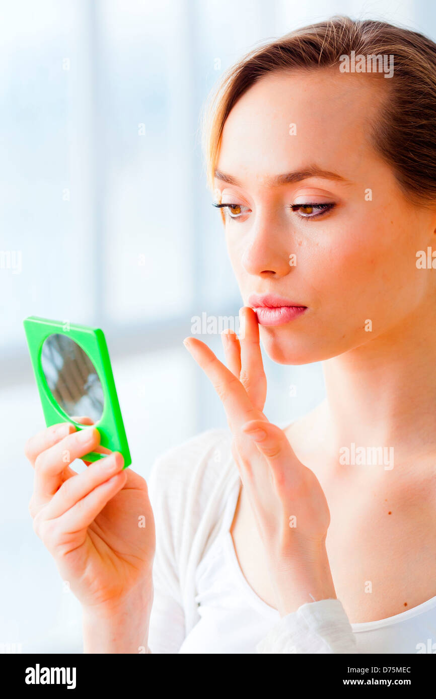 Young woman checking her face in the mirror Stock Photo - Alamy