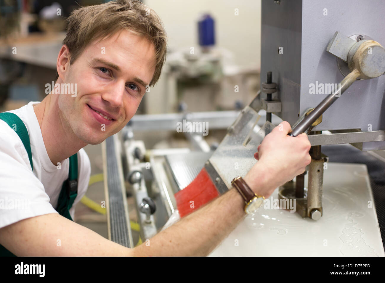 Worker in glazier's workshop operating a glass drilling or milling ...