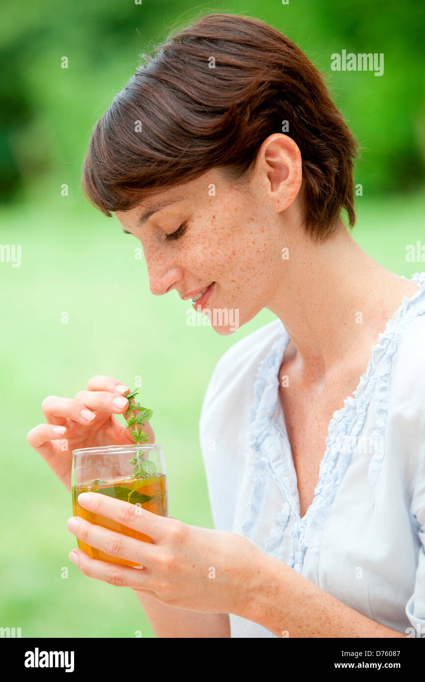 Woman drinking aromatic herbal infusion made from lemon balm leaves ...