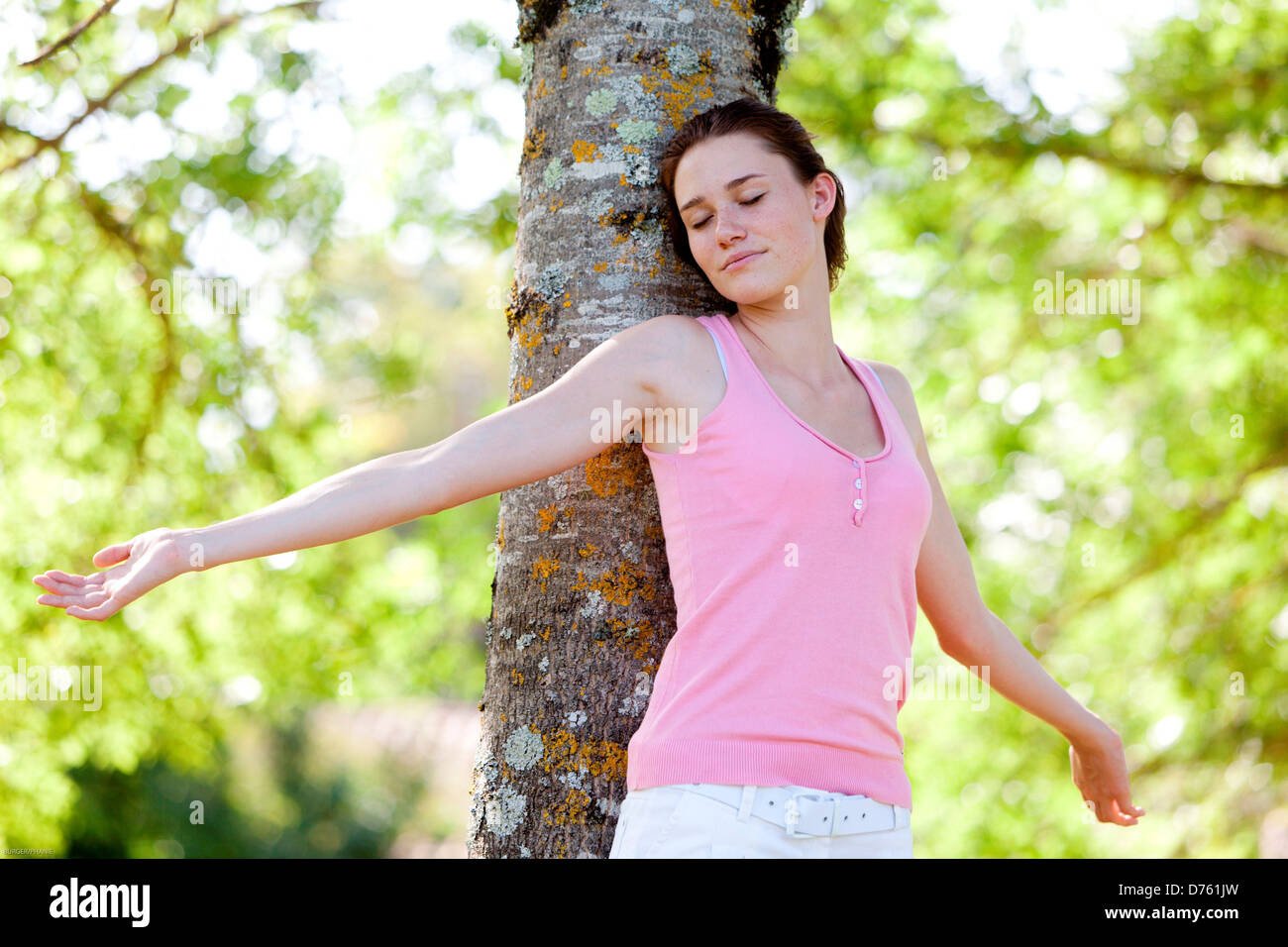 Woman leaning against a tree Stock Photo - Alamy