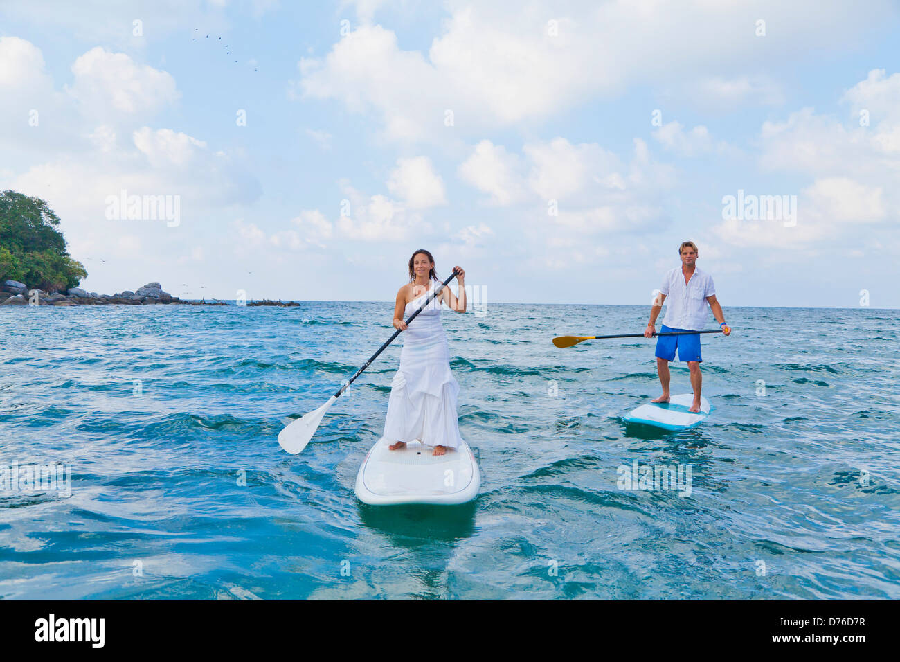 Dressed up man and woman riding paddle boards Stock Photo - Alamy