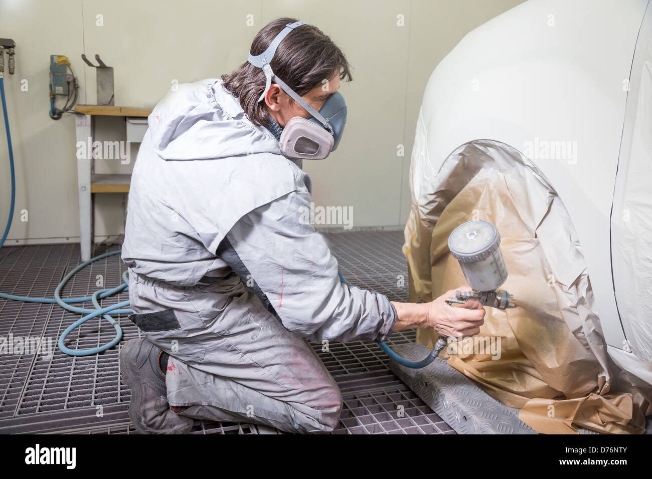 Car body painter spraying paint or color on bodywork in a garage or ...