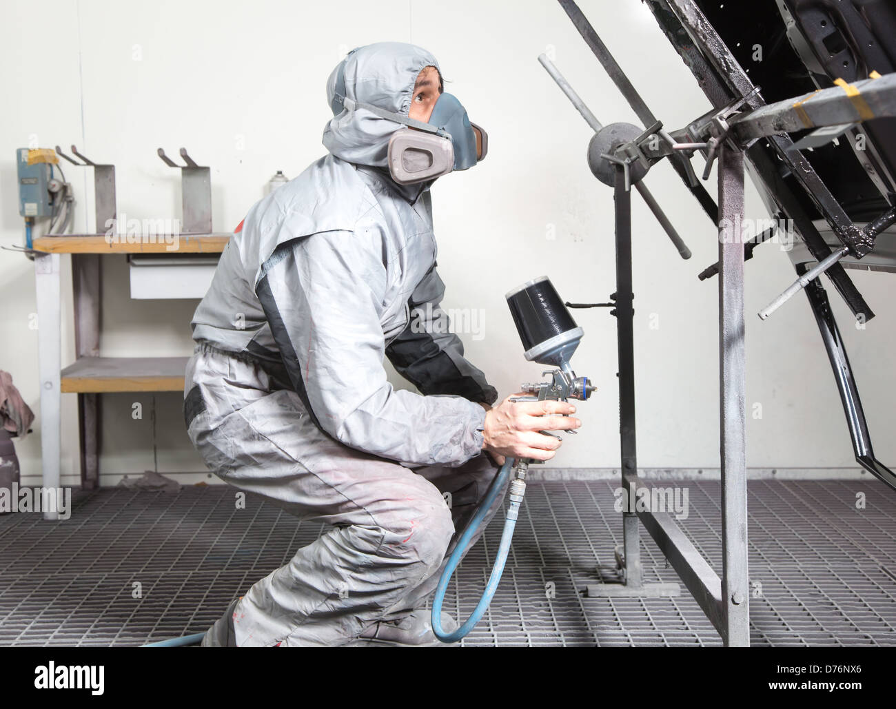 Car body painter spraying paint or color on bodywork in a garage or ...