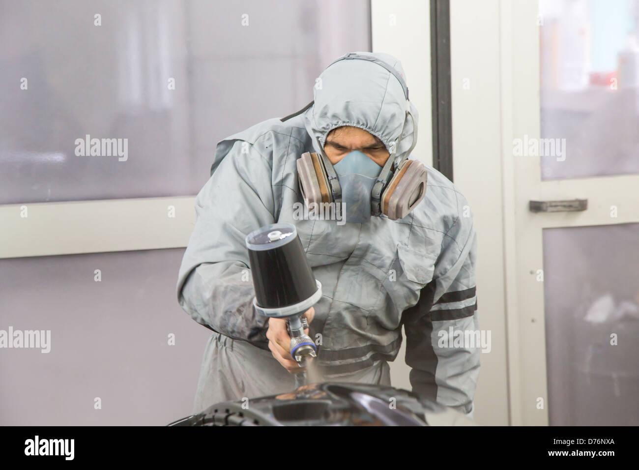 Car body painter spraying paint or color on bodywork in a garage or ...