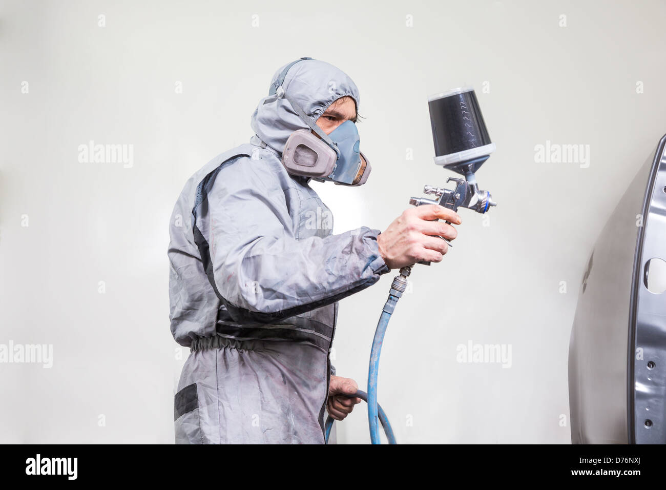 Car body painter spraying paint or color on bodywork in a garage or ...
