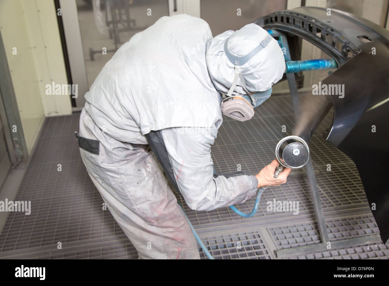 Car body painter spraying paint or color on bodywork in a garage or ...