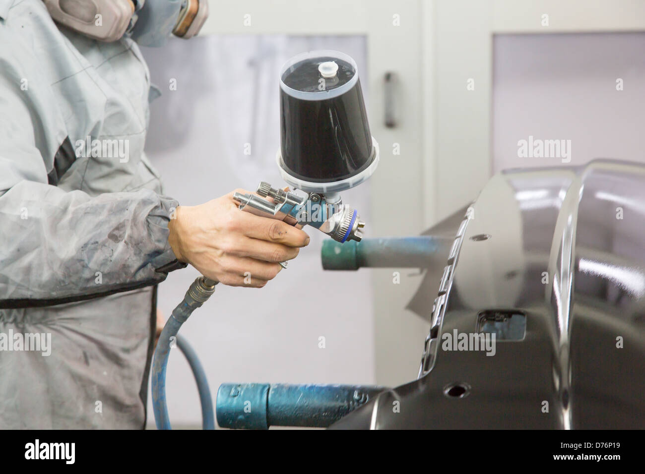 Car body painter spraying paint or color on bodywork in a garage or ...