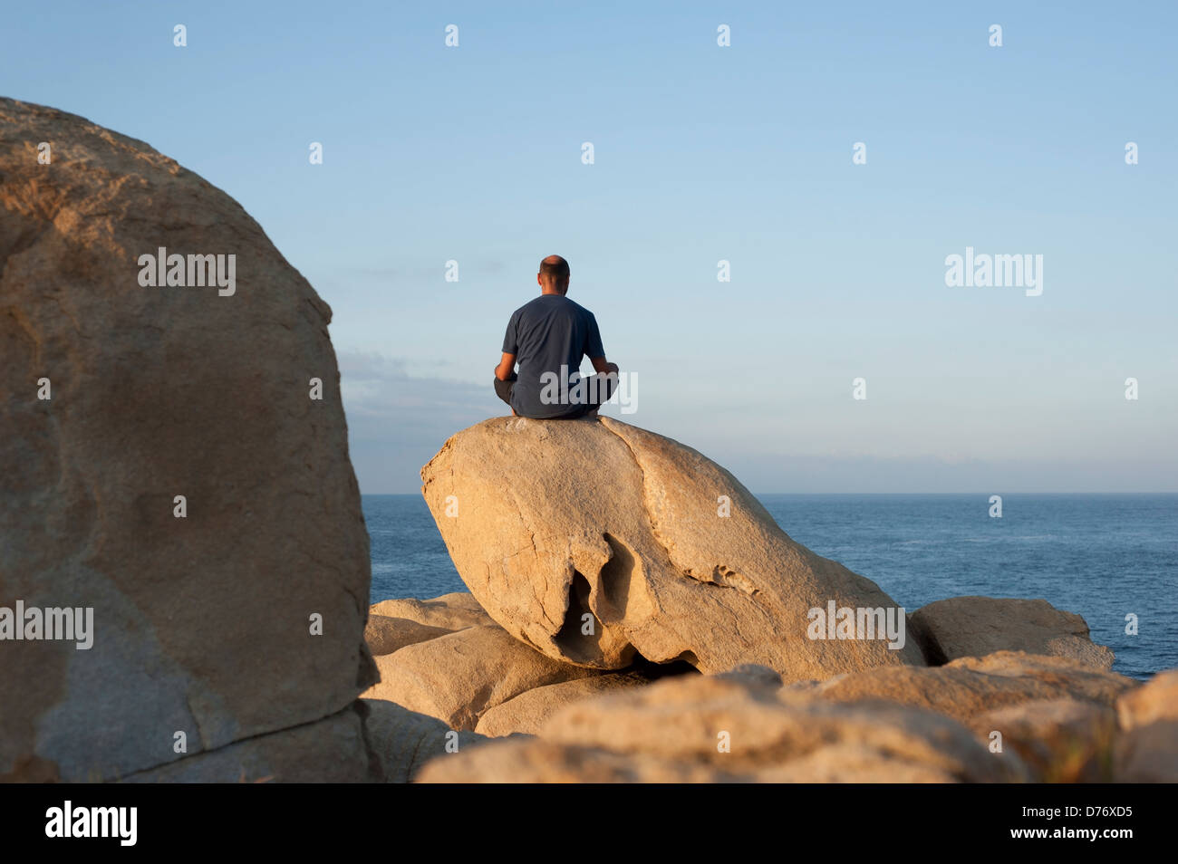 A man meditating on the rocks Stock Photo - Alamy