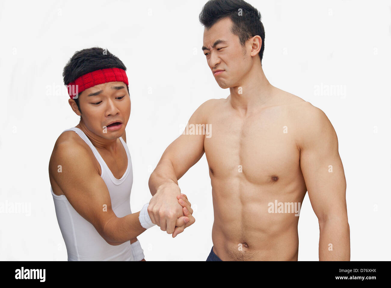 One young man beating another at arm wrestling, studio shot Stock Photo ...