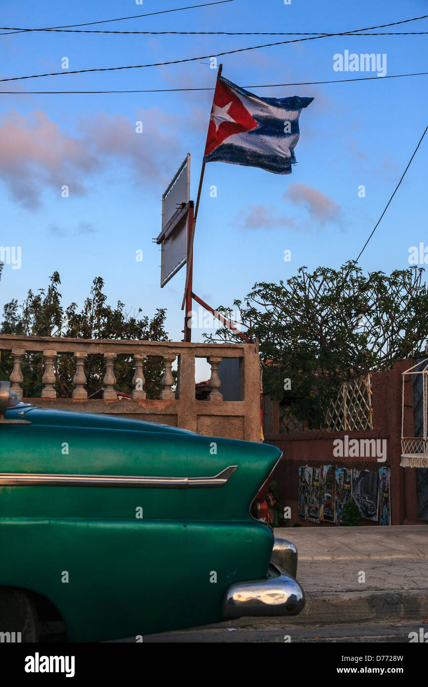 Cuban national flag with old american car in front Stock Photo - Alamy