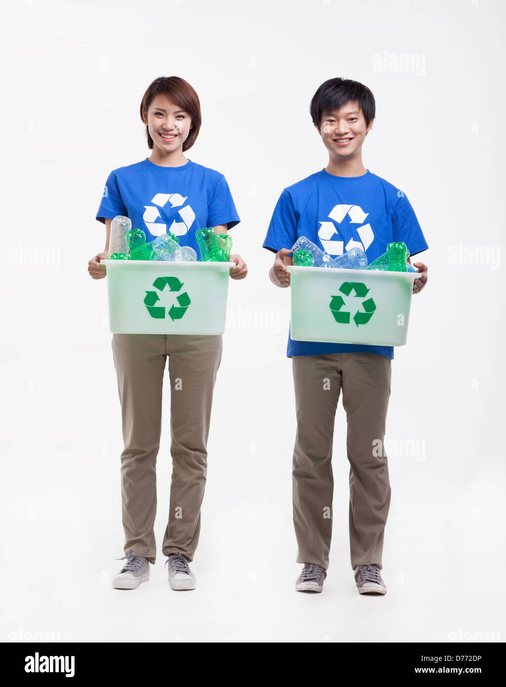 Portrait of two young people holding recycling bins, studio shot Stock ...