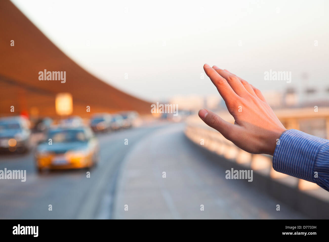 Hand of traveler hailing a taxi outside of the airport Stock Photo - Alamy