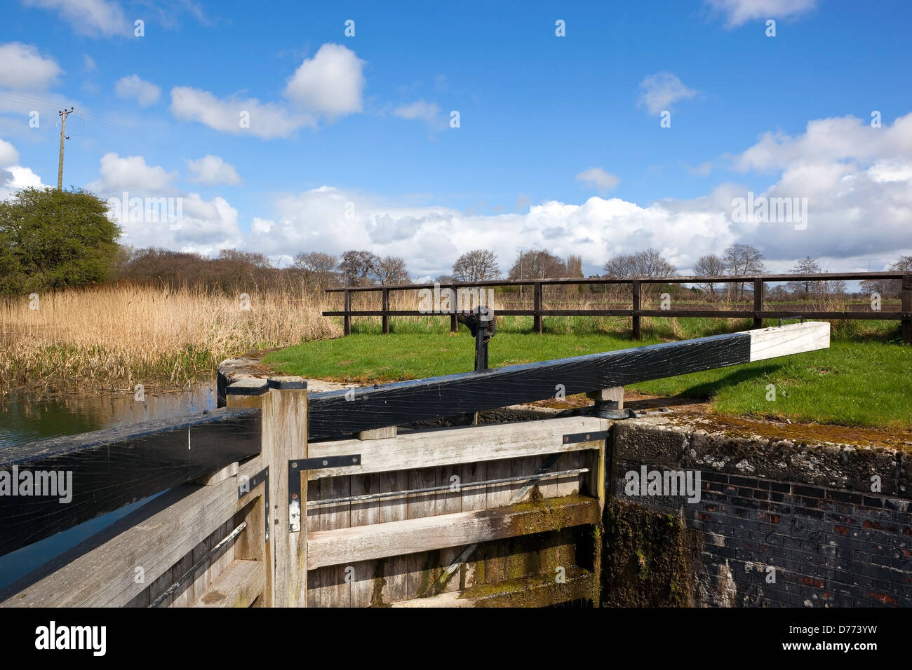 Wooden gates of a canal lock mechanism in a rural setting under a blue ...
