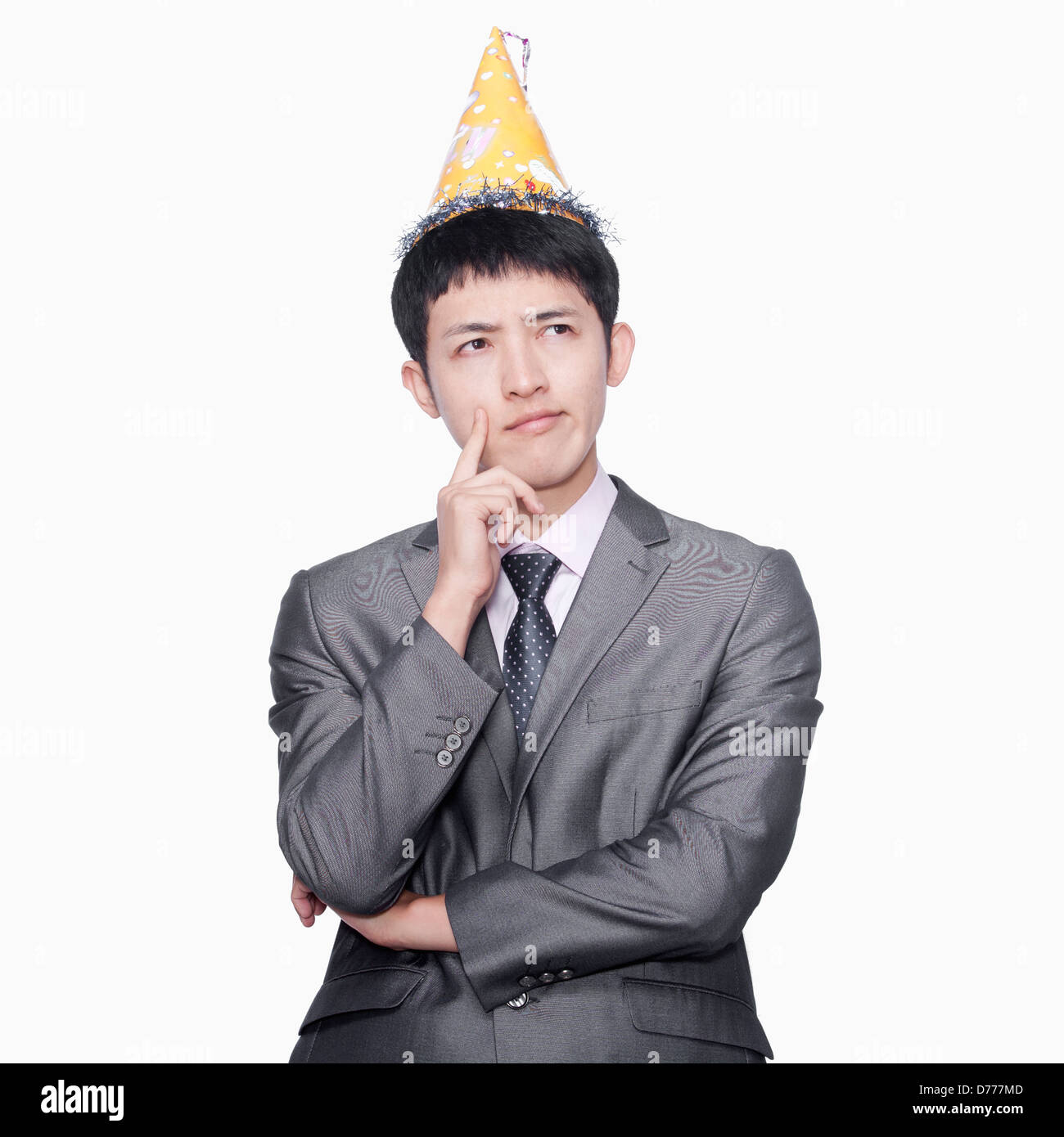 Businessman thinking, wearing party hat Stock Photo - Alamy